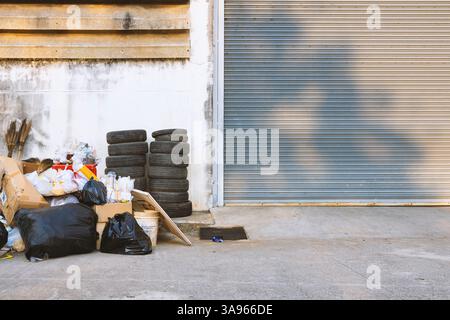 Piles of trash and overflowing bins against a dirty wall with recycling ...