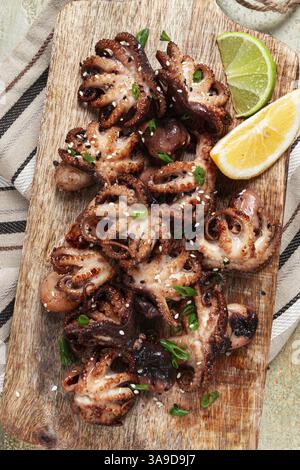Grilled baby octopus, with green onions, with lemon wedges, on a wooden ...
