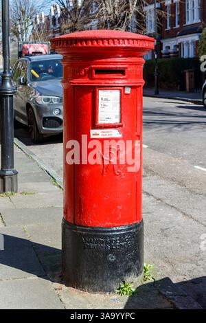 Traditional red circular Victorian post box on a residential street in ...