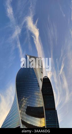 A modern architectural marvel with a curved, reflective glass facade ...