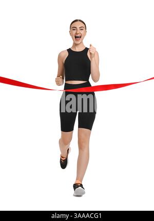 Happy sportswoman crossing red finish line ribbon on white background ...