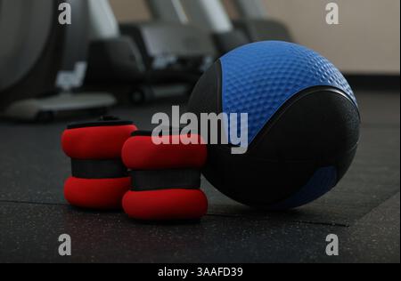 Blue medicine ball and ankle weights on floor in gym, space for text ...