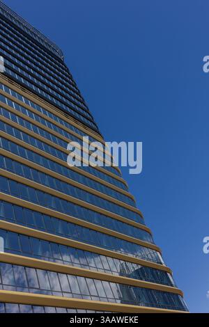 A close-up of a tall skyscraper corner against the sky. Blue glass ...
