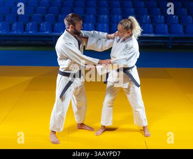 Martial arts. Sparing Portners. Sport man and woman in white kimono train judo throws and ...