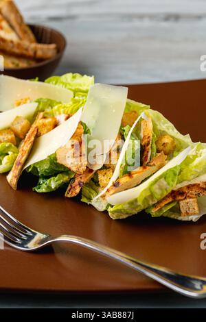 Plate with tasty Caesar salad on color wooden background, closeup Stock ...