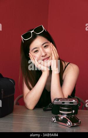 Happy Asian woman sits on wooden balcony terrace with cute small cat ...