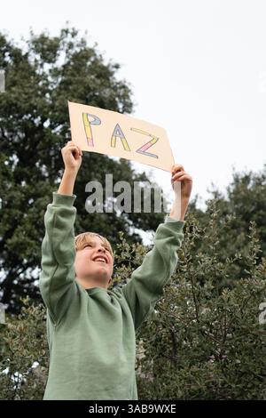 Child holding a paz sign, advocating for peace and harmony in a park ...