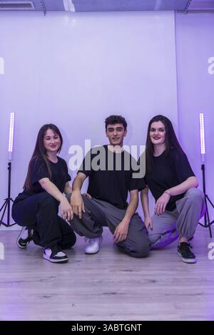 Three young dancers crouching in a dance studio, showcasing their ...