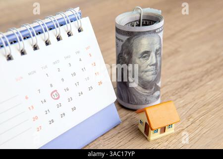 A calendar, rolled stack of US hundred dollar bills and a small toy car ...