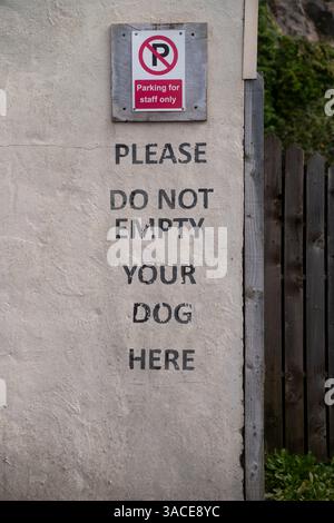 A stencil sign saying PLEASE DO NOT EMPTY YOUR DOG HERE on the side of ...