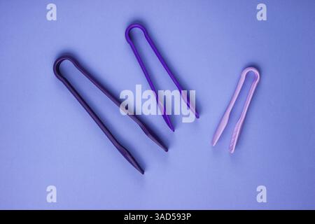 Kitchen tongs on purple paper background. Top view Stock Photo - Alamy