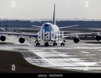 A large airplane, possibly a Boeing 747, taxiing on an airport runway ...