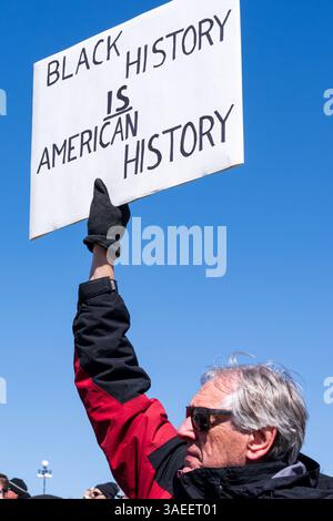 A demonstrator holds a sign during rally in opposition to COVID-19 ...