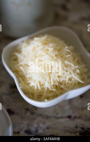 Shredded mozzarella and cheddar cheese, in white bowls. Grated low ...