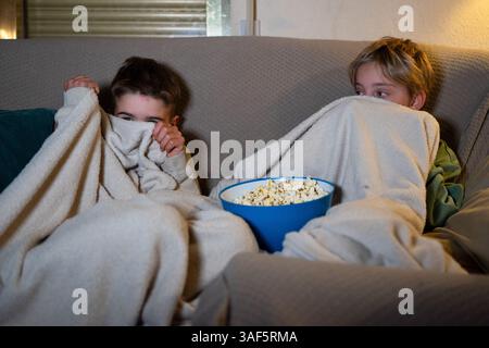 Watching movie while eating popcorn under blanket Stock Photo - Alamy