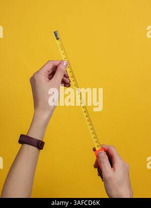 Female hands take measurements with industrial tape measure on purple ...