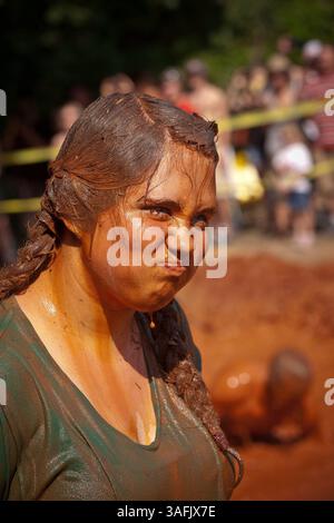 A competitor reacts after diving into a pool of mud during the Mud Pit ...