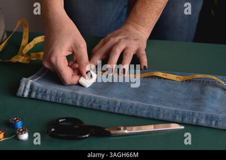 Seamstress marking jeans length for hemming Stock Photo - Alamy