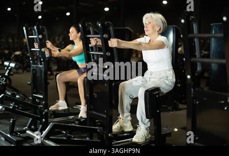 Senior woman uses leg abduction machine to strengthen muscles Stock ...