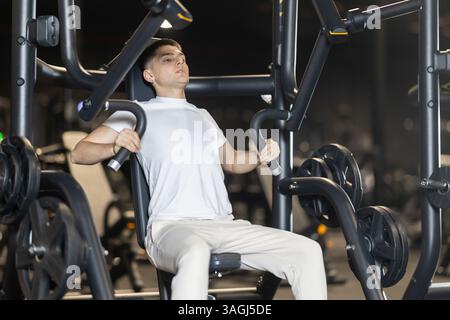 In gym, man uses chest press machine to strengthen arm muscles Stock ...