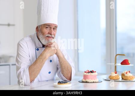 Elderly pastry chef at table with desserts in kitchen Stock Photo - Alamy