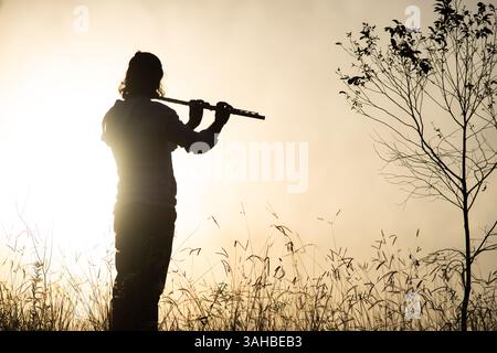 a piper playing a c flute against a hard sun in the background amidst a ...