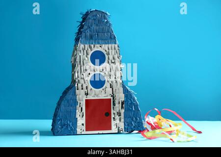 Bright pinata in shape of spaceship on table against orange background ...