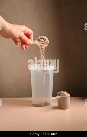 Pouring chocolate protein powder in a shaker, food supplement concept ...