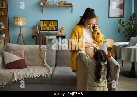 A pregnant woman with her daughter in a cozy home atmosphere. Waiting ...