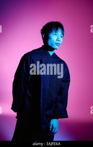 Handsome asian man stands confidently against a bold orange backdrop ...