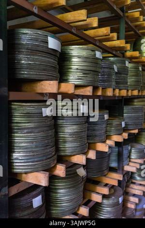 A collection of metal film reels stacked neatly on wooden shelves ...
