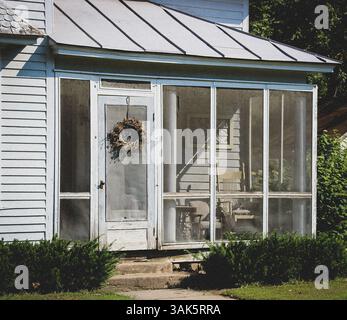 A cozy peaceful front porch of a house with adirondack chairs and ...