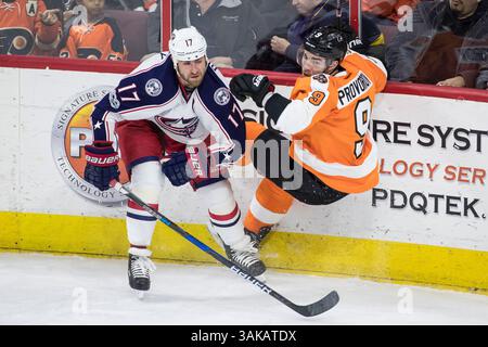 Columbus Blue Jackets defenseman Ivan Provorov, right, passes the puck ...