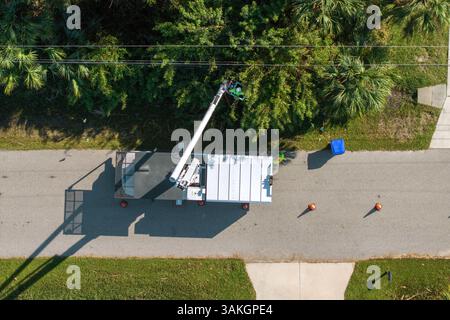 Electricity outage prevention. Electrician worker trimming tree around ...