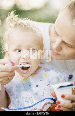 Mom feeds her baby girl with a spoon on baby chair Stock Photo - Alamy