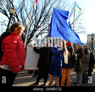 A large European Union flag waves on a tall white pole against a clear ...