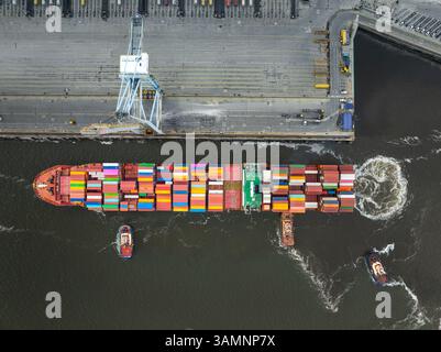 Tug boats push and pull a huge container vessel Stock Photo - Alamy