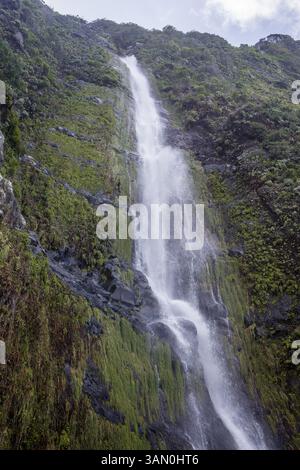 A majestic waterfall cascades down a rocky cliff face, situated beneath ...