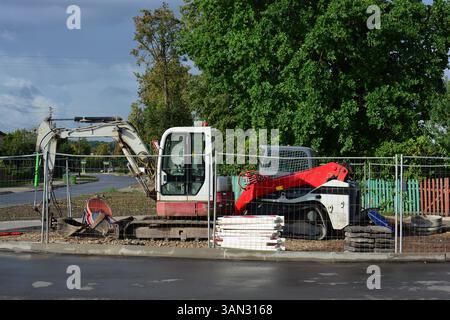 Mini caterpillar excavator digging and pushing ground in street ...