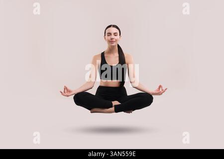 Young woman levitating during meditation on light blue background ...