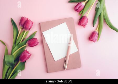 Top view with pink tulips and notebook on pink background. Business ...