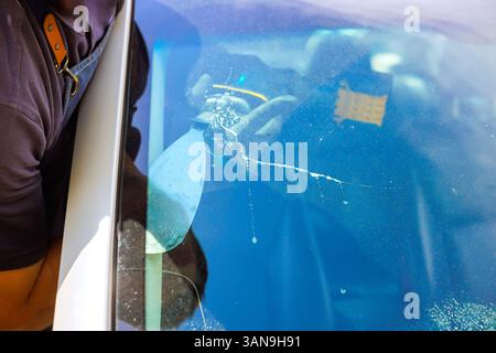 Specialist fixing crack on car windshield in repair shop Stock Photo ...