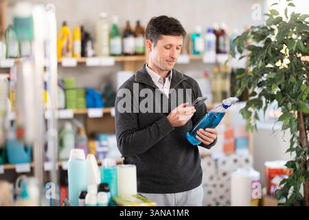 Middle-aged man scanning QR-code on cleaning spray at supermarket Stock ...
