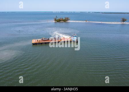 Aerial view of a tugboat pilot attempting to free a grounded barge in ...