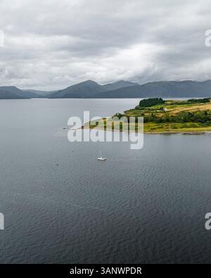 Aerial view of serene Shuna Island on tranquil Loch Linnhe with a boat ...
