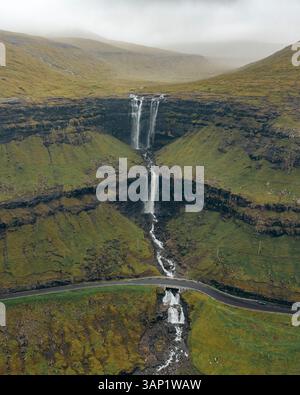 Aerial view of cascading Fossá waterfall cutting through vibrant green ...