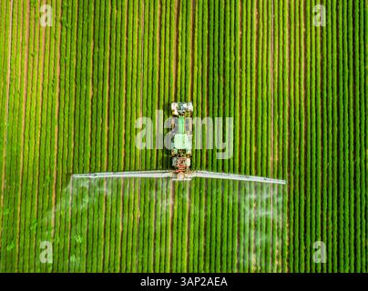 Aerial view of a tractor spraying fertiliser across an agricultural ...