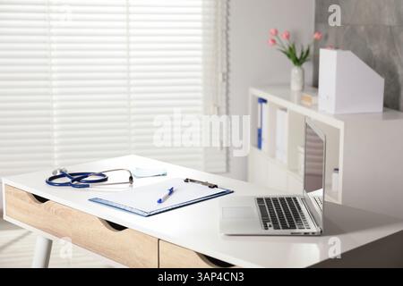 Doctor's workplace. Laptop, stethoscope and stationery on white table ...