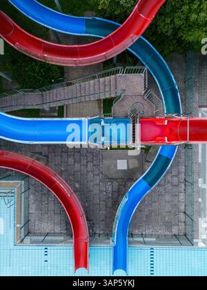 Aerial view of public pools with red and blue waterslides surrounded by ...