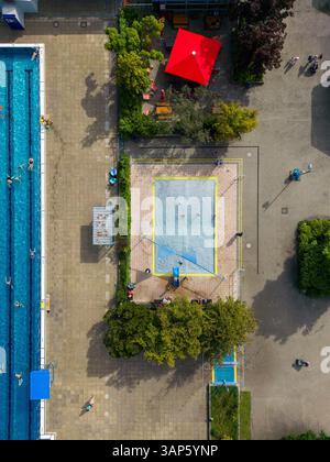 Aerial view of public pools with people swimming in vibrant blue water ...